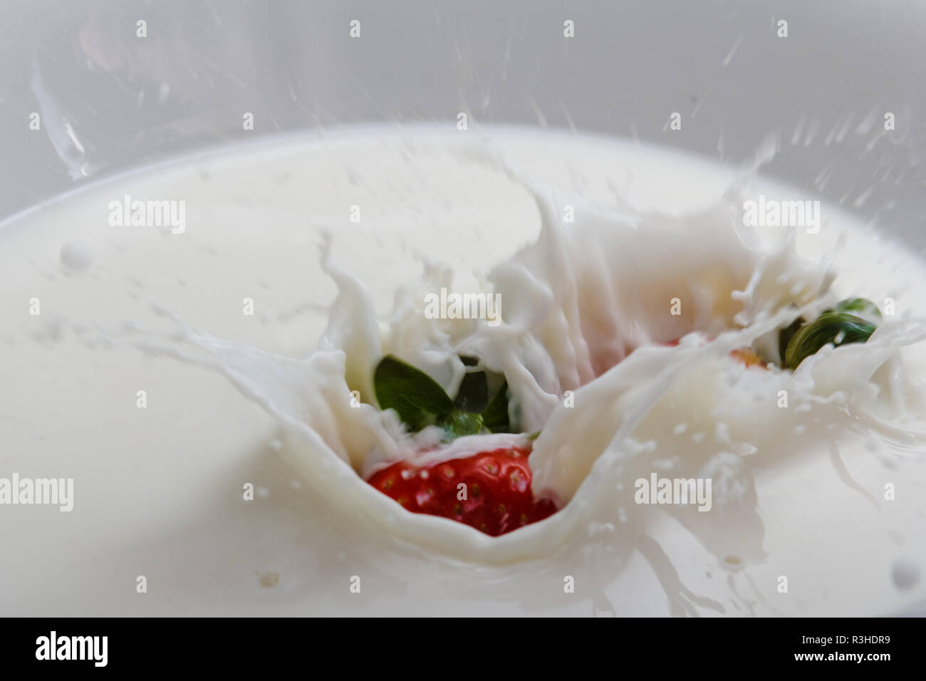 strawberry falling into milk 3 Stock Photo - Alamy