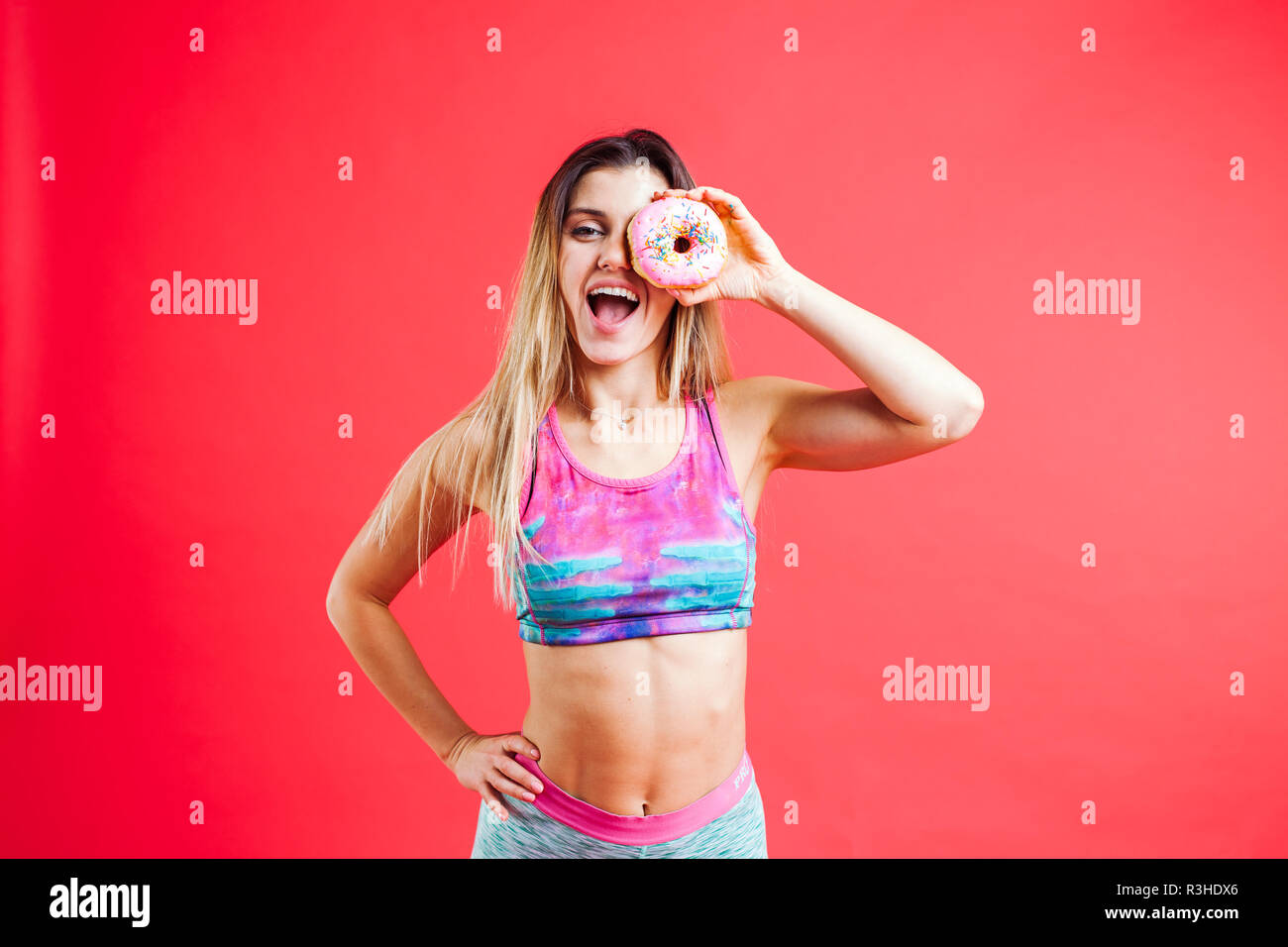SPORTY attractive girl in ultra violet with donuts isolated on red ...