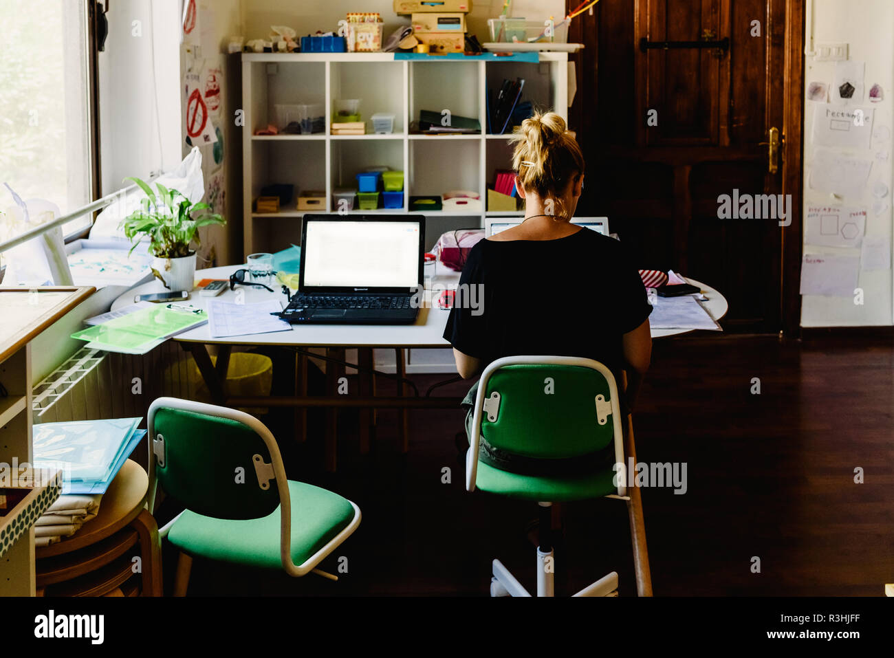 Woman from behind sitting at her desk working with computer in casual ...