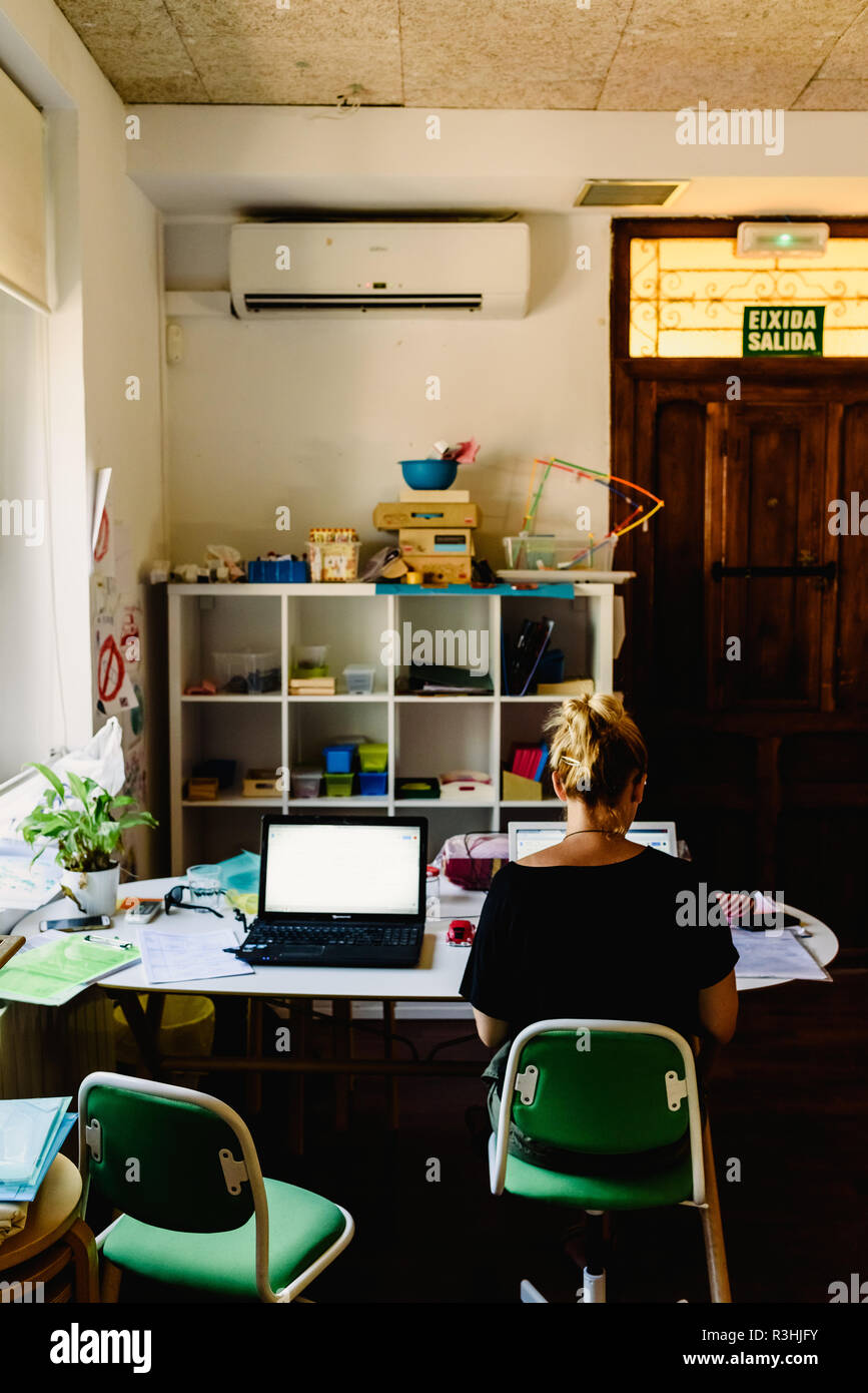 Woman from behind sitting at her desk working with computer in casual ...
