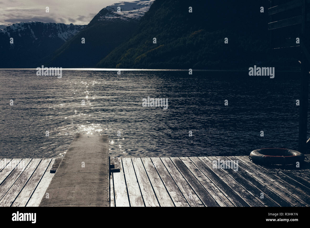 Wooden path over the water of a lake with snowy mountains Stock Photo ...