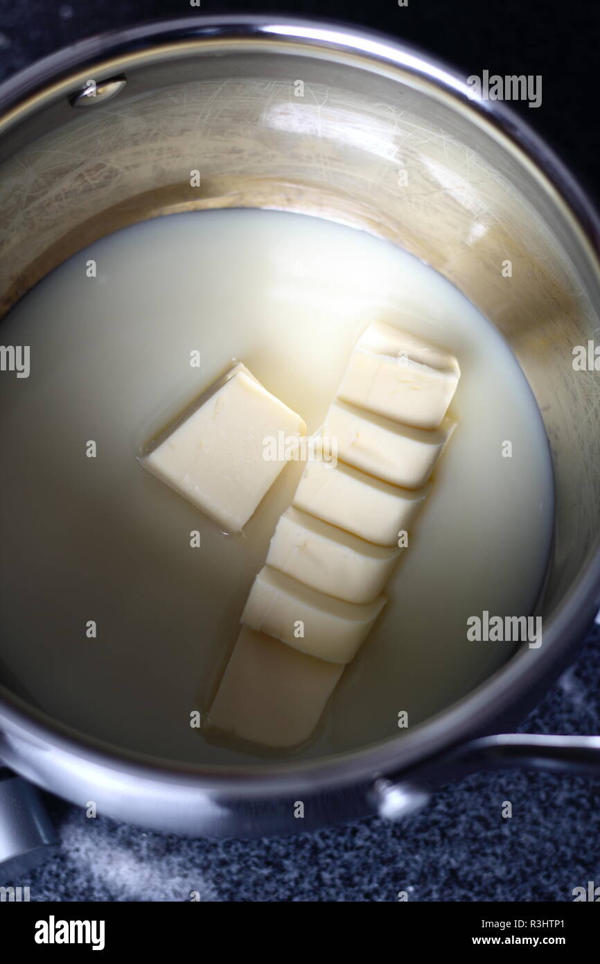 Adding diced butter into pan with sweetened condensed milk. Making ...