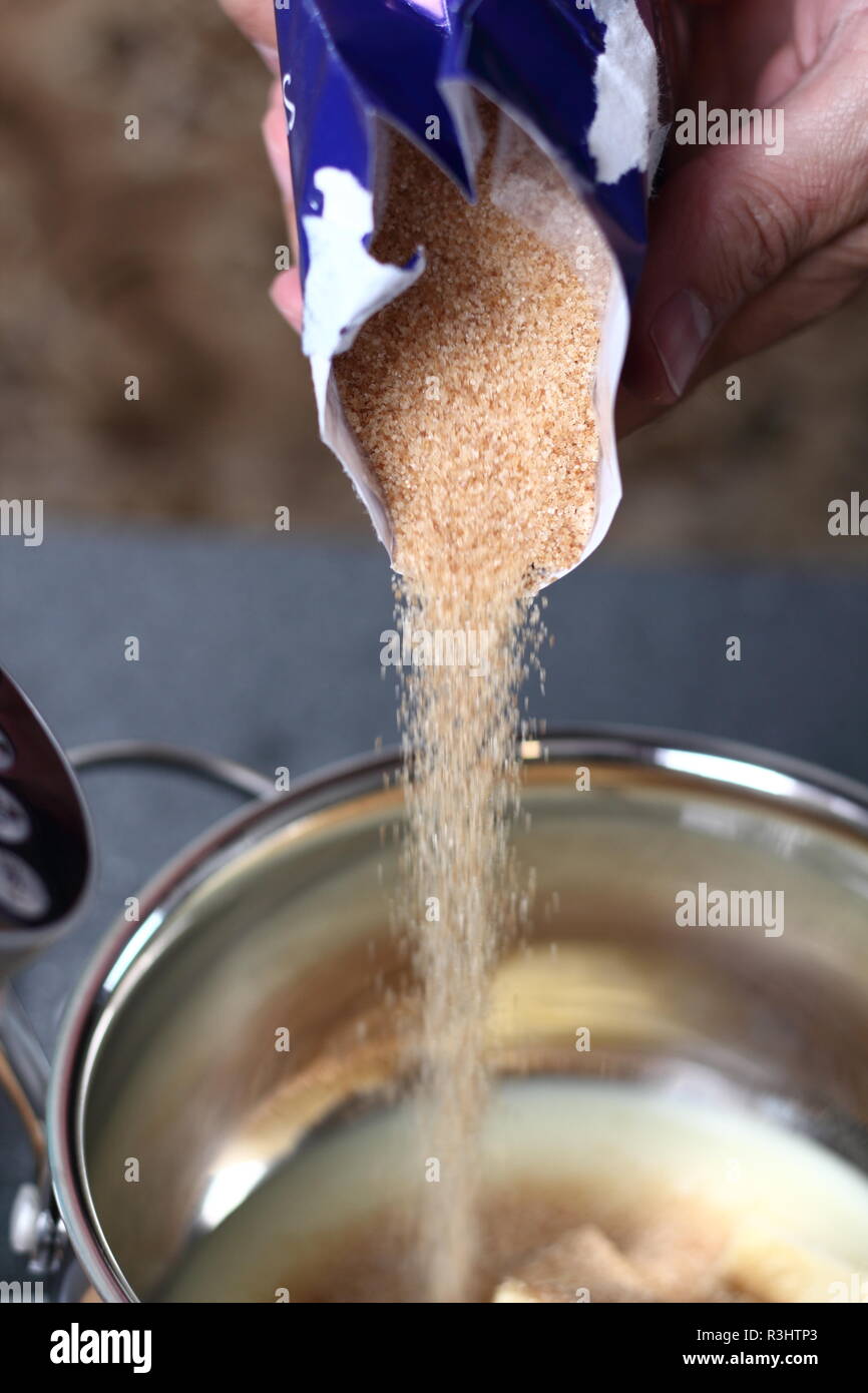 Pouring brown sugar into condensed milk with diced butter. Making ...