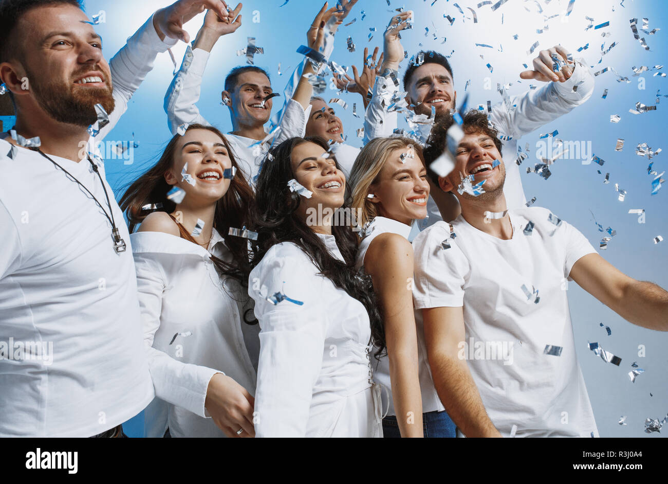 Group of cheerful joyful young people standing and celebrating together ...