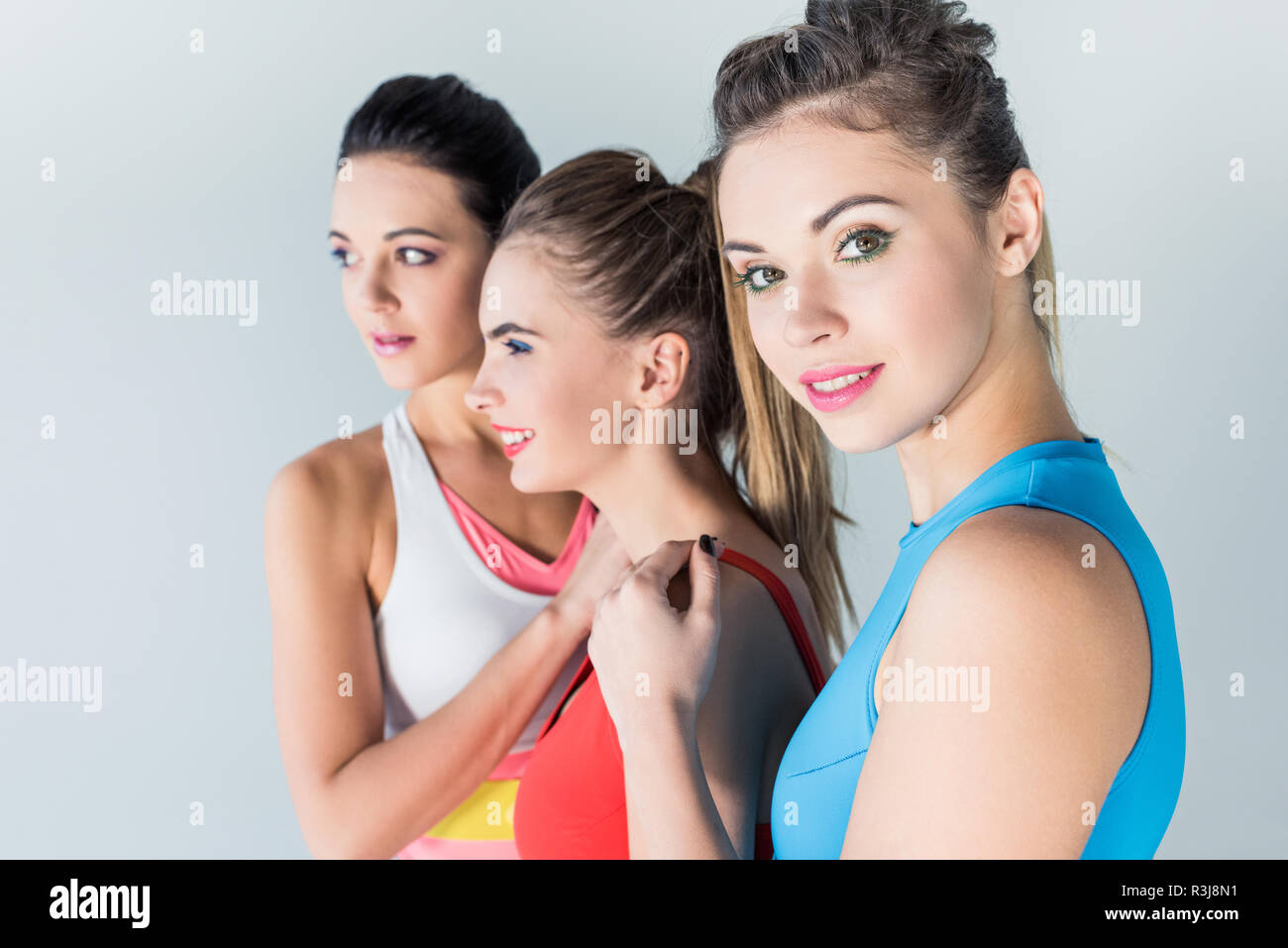 attractive young sportswomen in sportswear standing together isolated ...