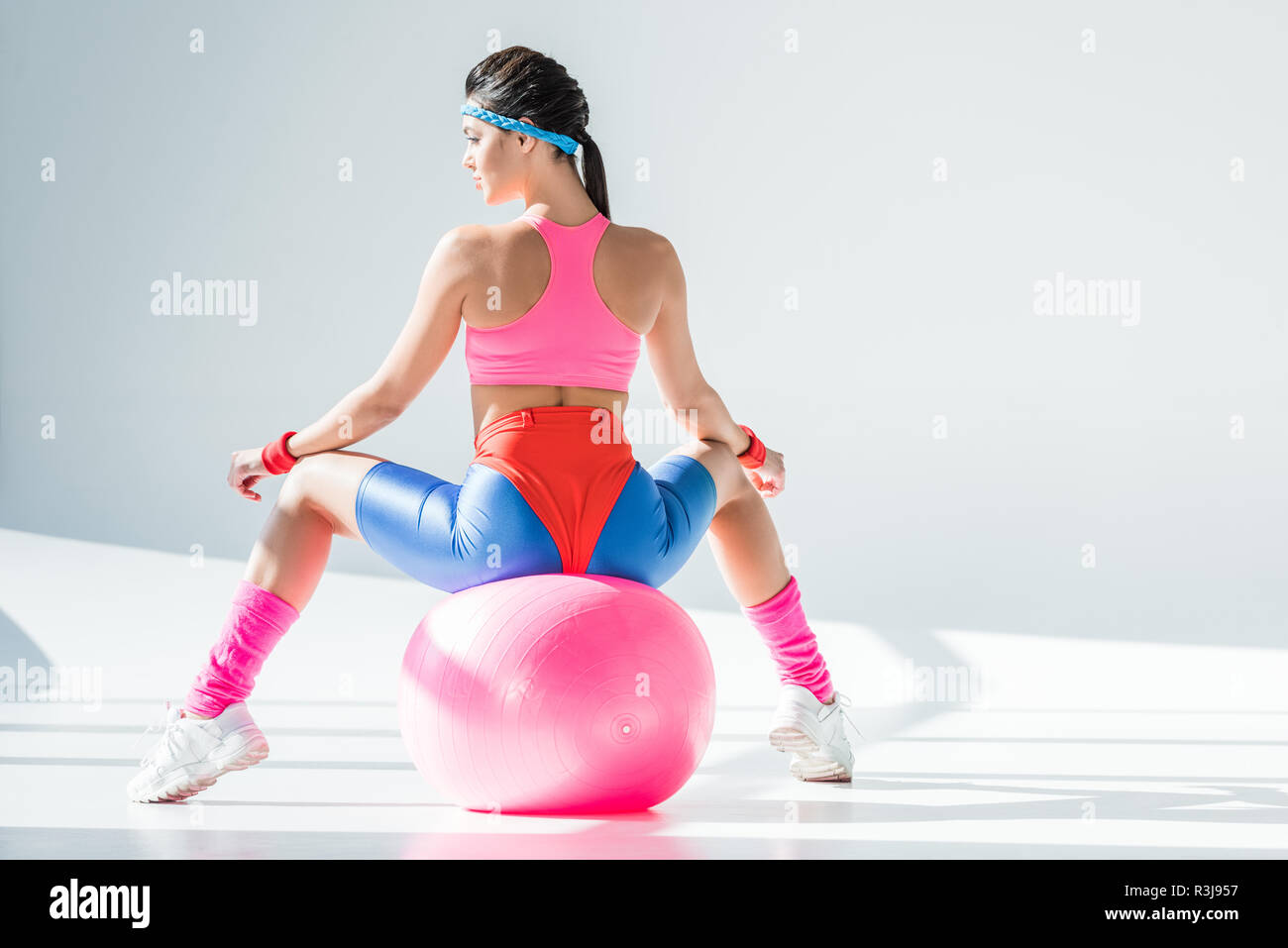 back view of athletic young woman sitting and exercising on fitness ...
