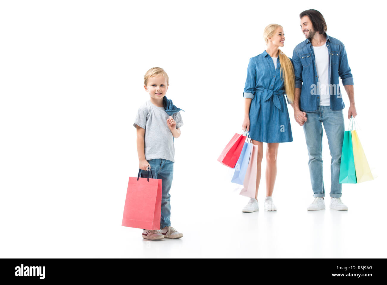 son holding bag after shopping and looking at camera, parents standing ...