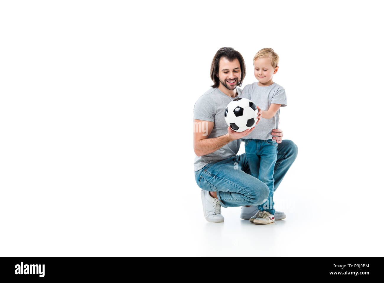 Daddy and his little child hugging each other and looking at soccer ...