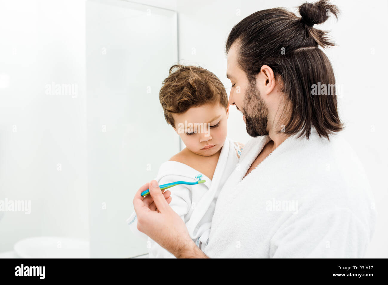 dad showing toothbrush with toothpaste to toddler son Stock Photo - Alamy