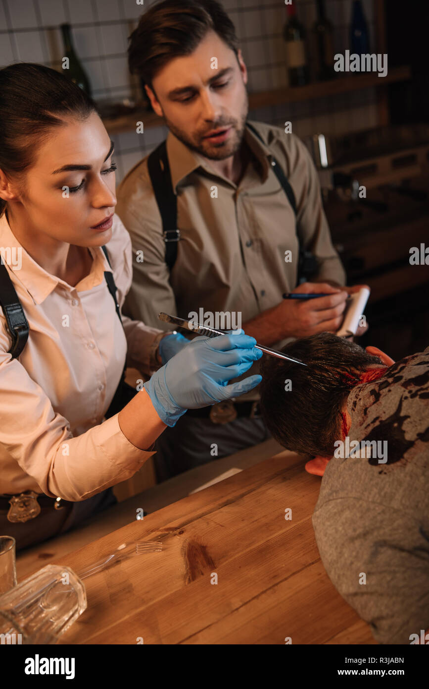 cropped view of concentated female and male detectives collecting ...
