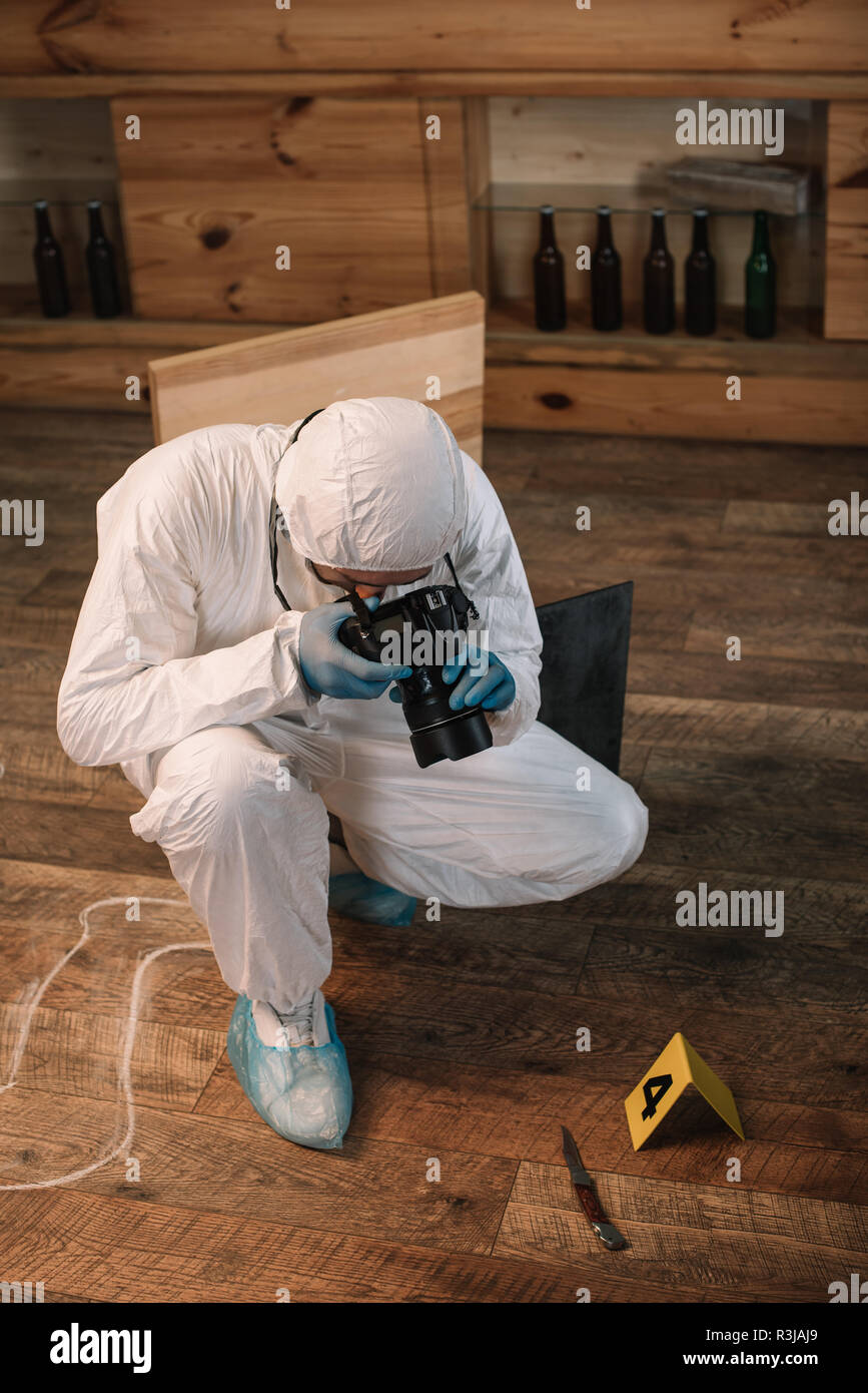 forensic investigator documenting evidence with camera at crime scene ...