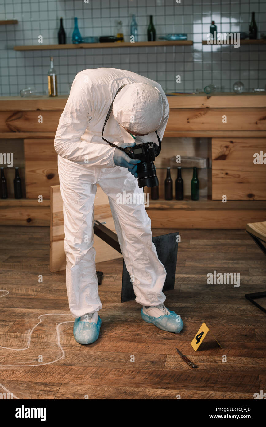 forensic investigator documenting evidence with camera at crime scene ...