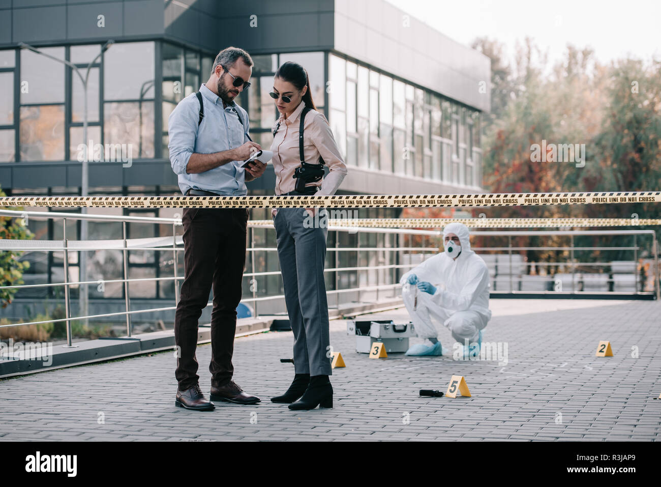 female and male detectives review their records at crime scene Stock ...