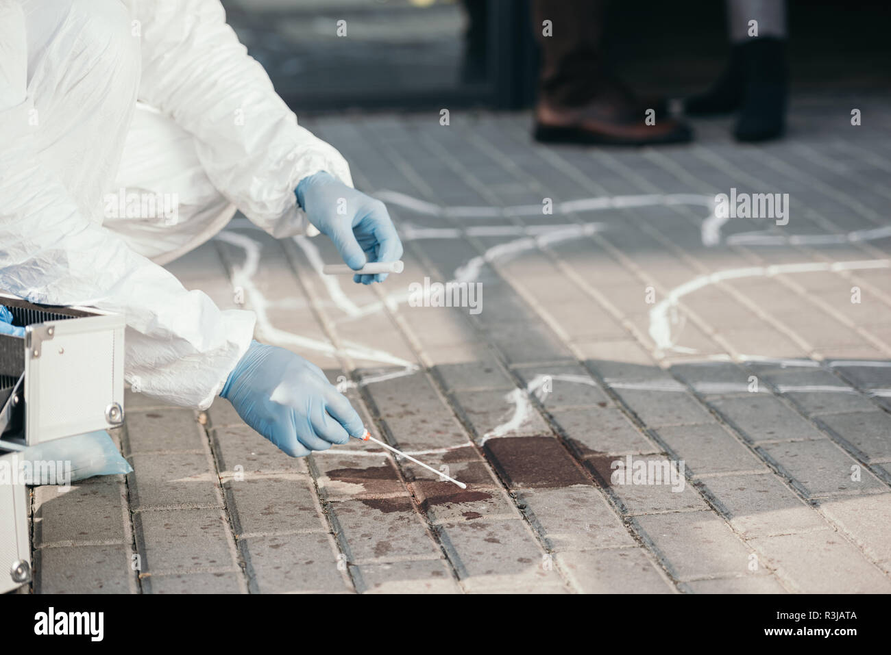 male criminologist in protective suit and latex gloves collecting blood ...
