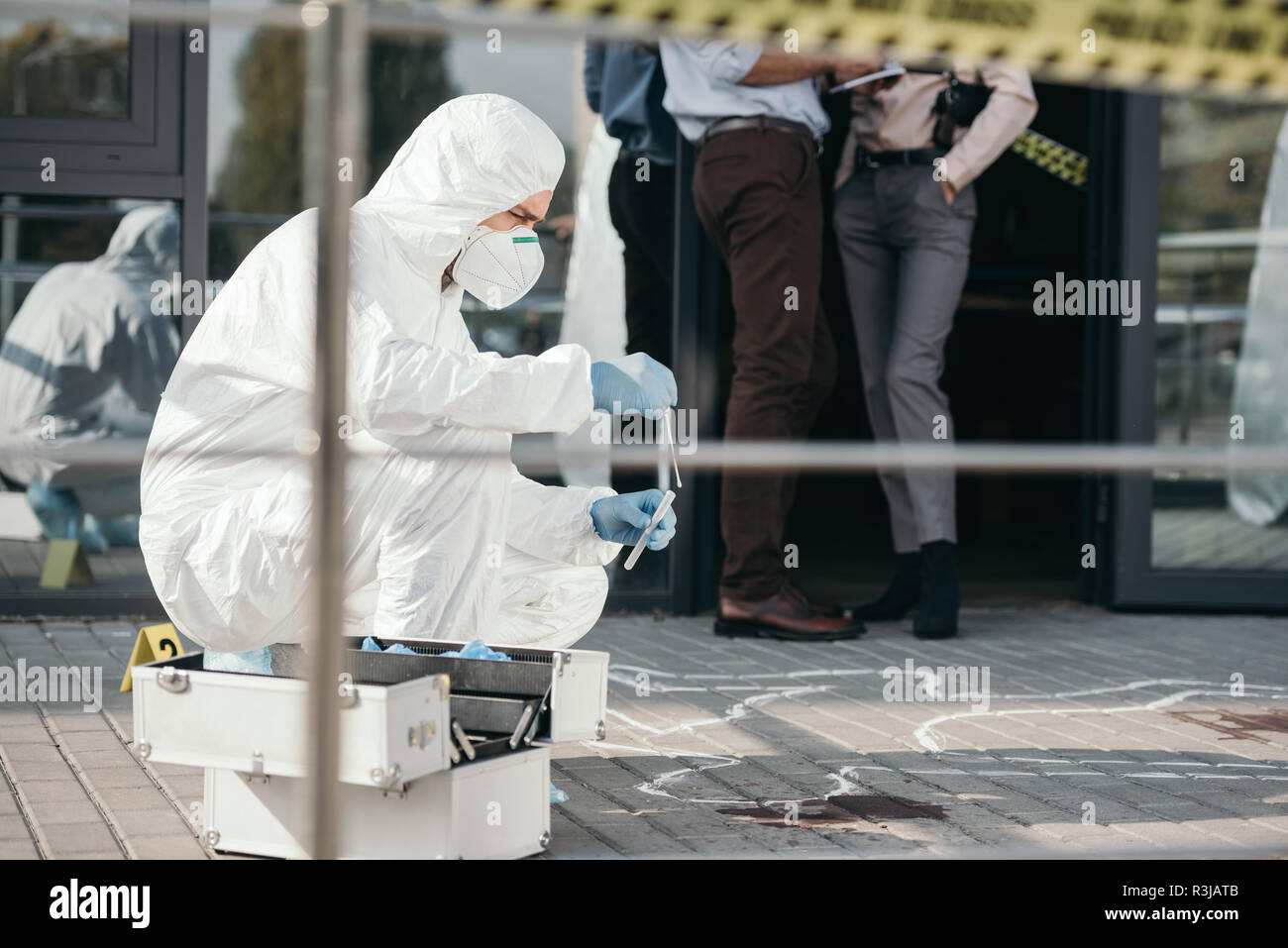 male criminologist in protective suit and latex gloves collecting evidence at crime scene Stock ...