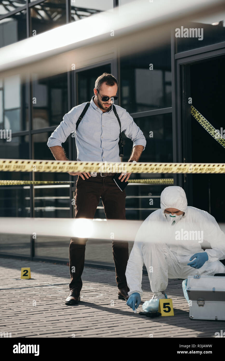 male detective looking at work of criminilogist Stock Photo - Alamy
