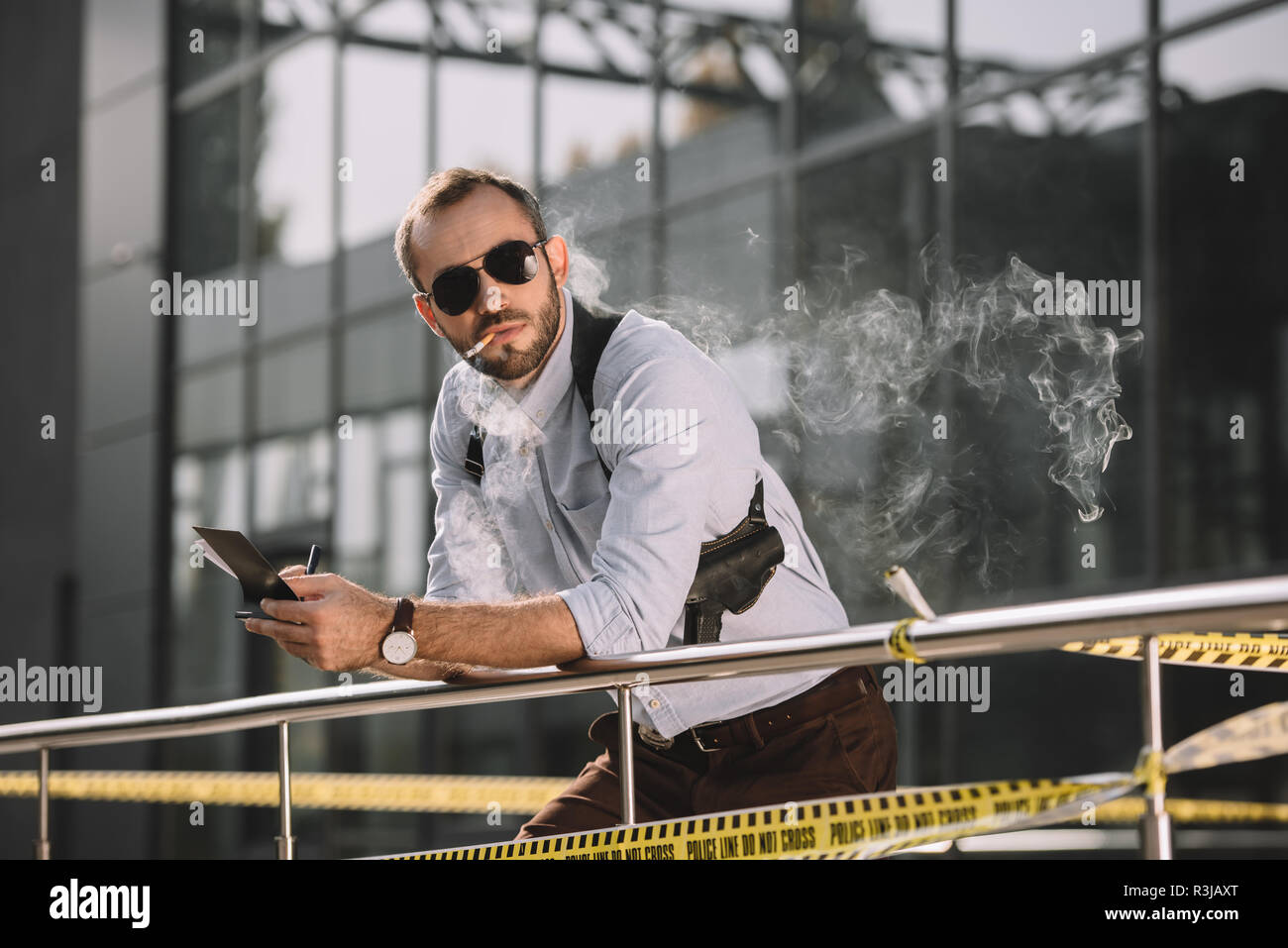 male detective smoking and making notes leaning on the fence Stock ...