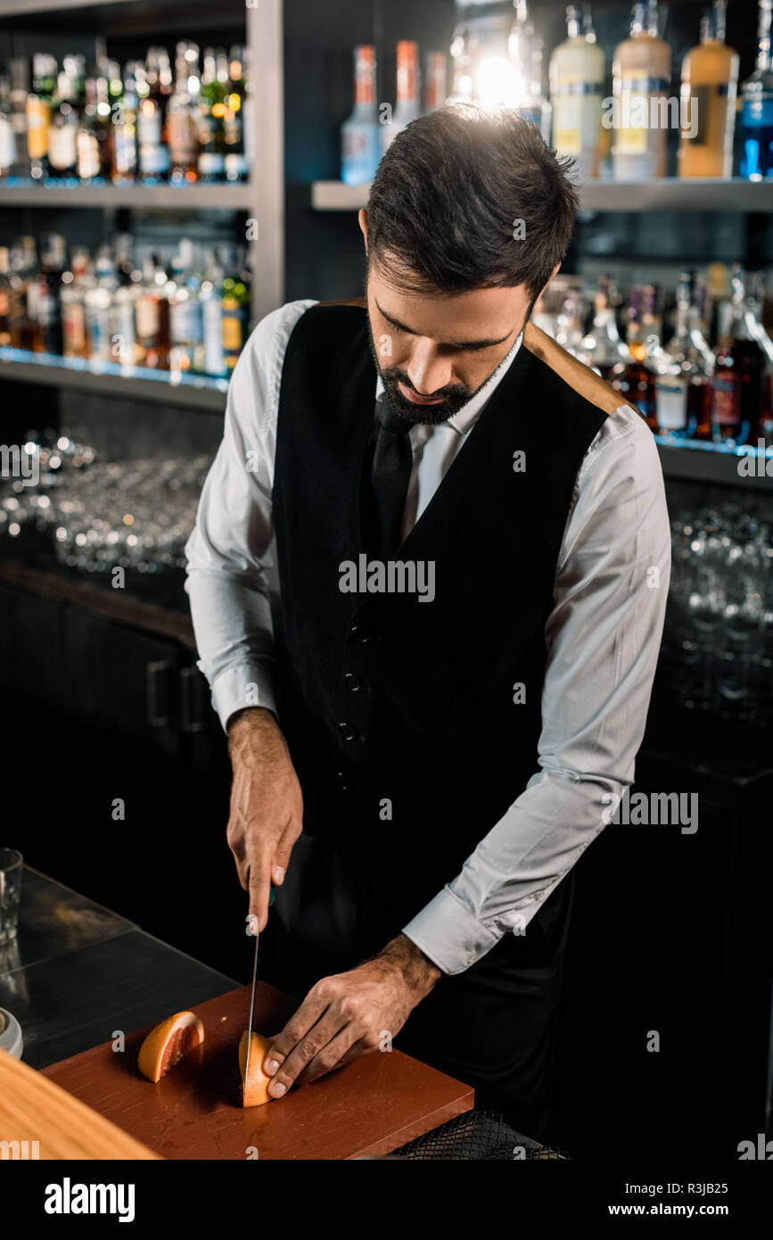 Bartender standing in bar and cutting fruit Stock Photo - Alamy