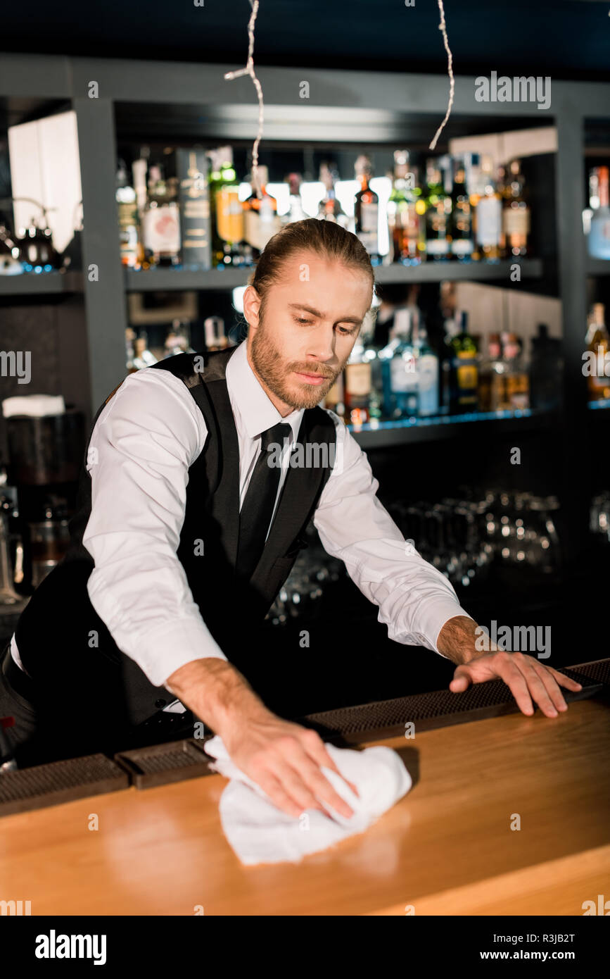 Handsome barman cleaning wooden bar counter with white napkin Stock ...