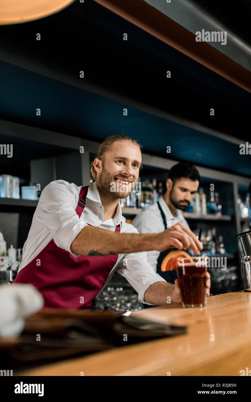 handsome smiling bartender serving cocktail at wooden counter Stock ...