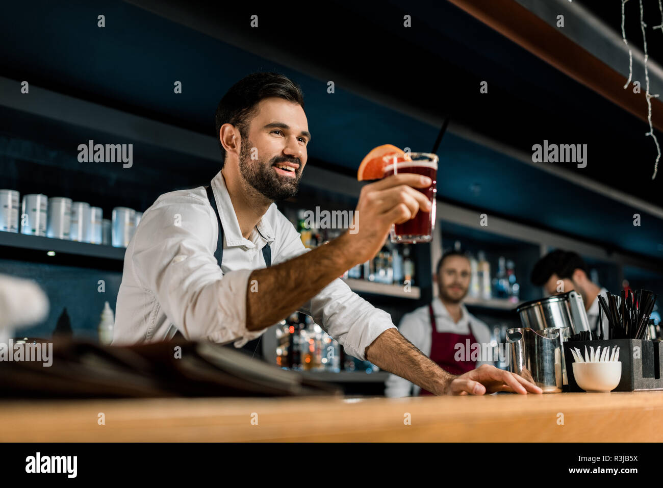 smiling bartender serving cocktail at wooden counter Stock Photo - Alamy