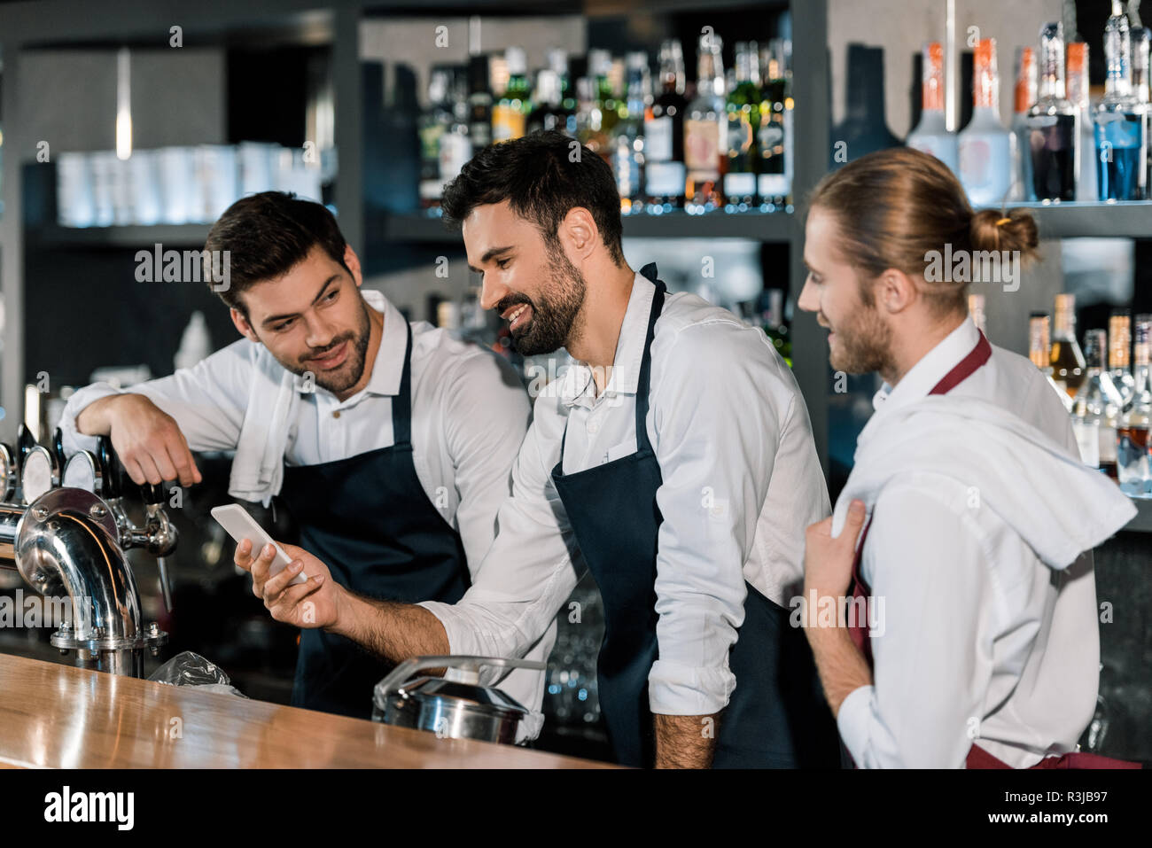 handsome adult barmen using smartphone at workplace Stock Photo - Alamy