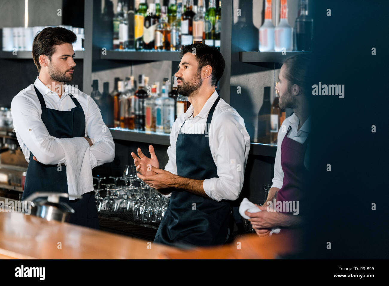barmen in aprons standing and communicating at workplace Stock Photo ...