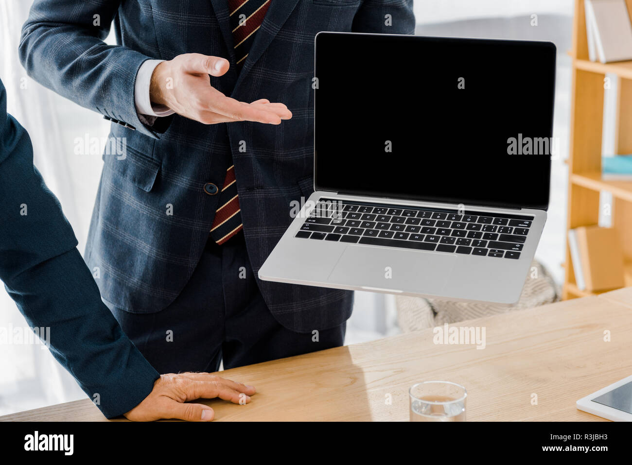 male insurance agent holding laptop with blank screen in office Stock ...