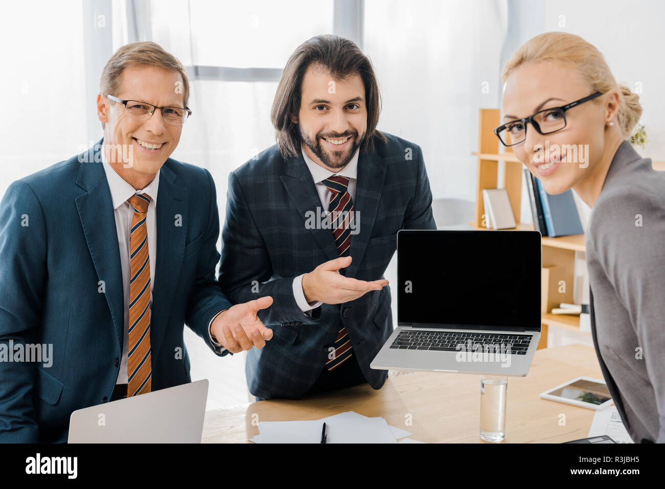 young smiling male insurance agent standing with workers and pointing ...