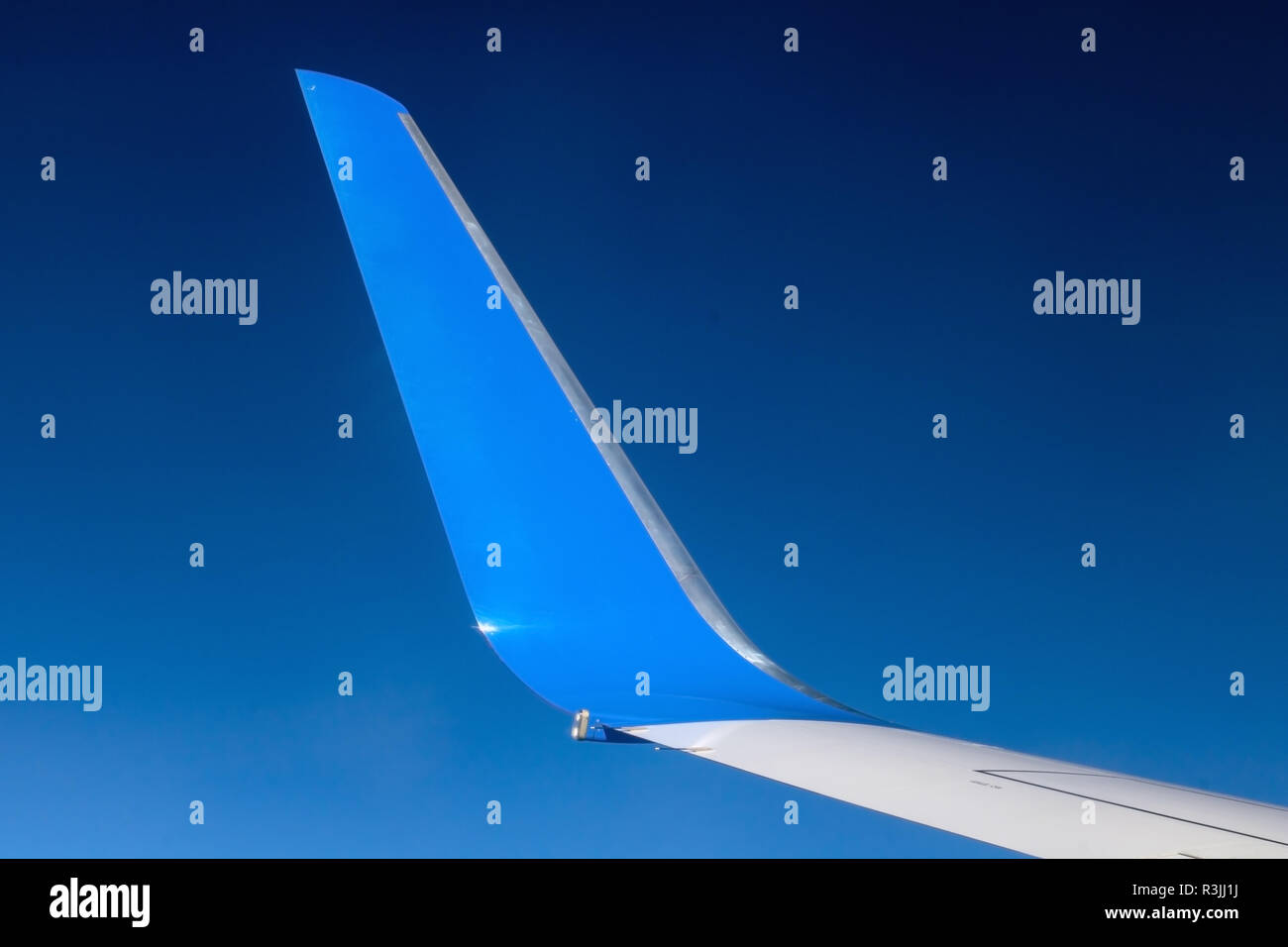 The blue winglet on a wing of plane when a flight in a blue sky. Part ...