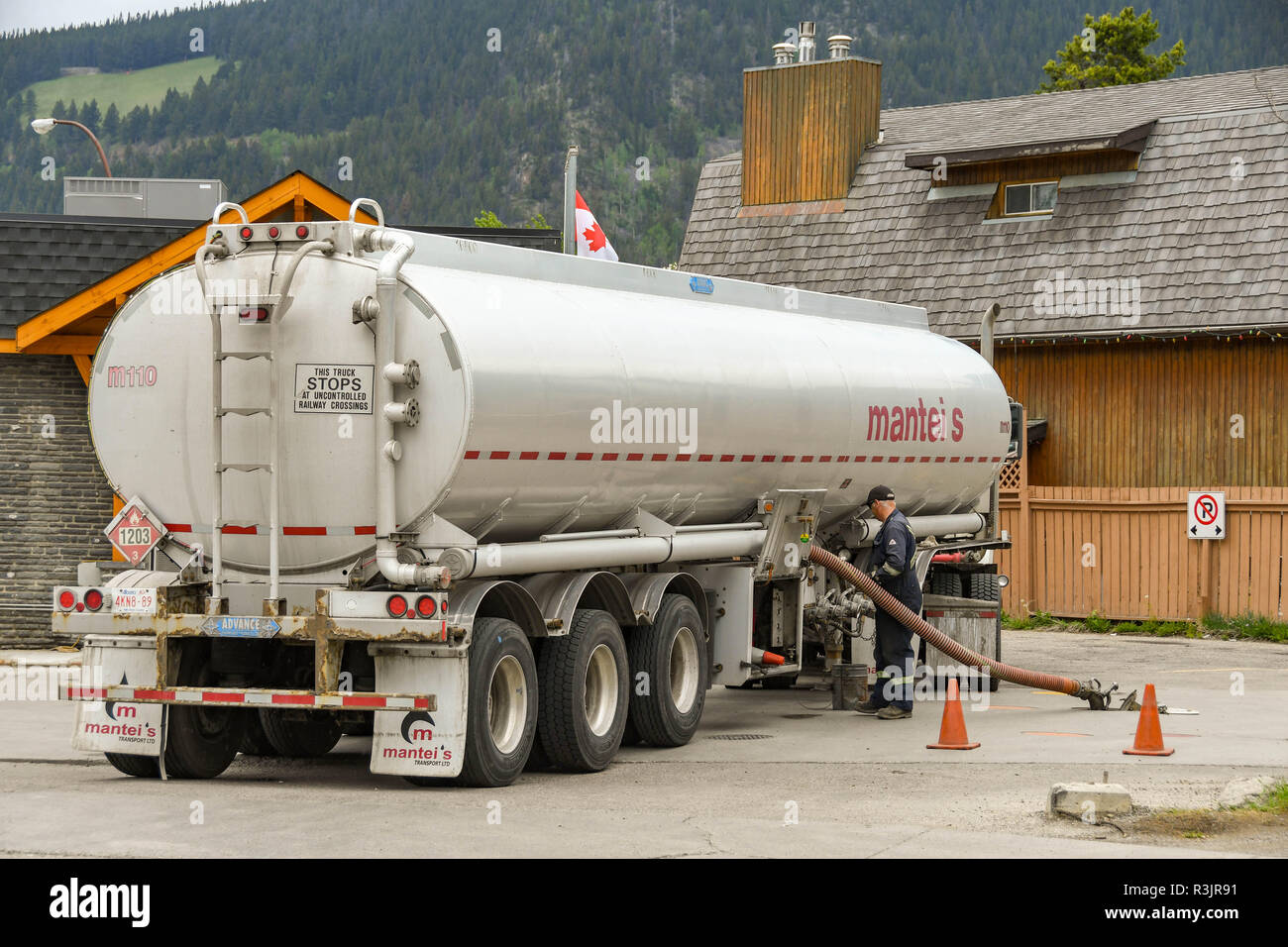 BANFF, AB, CANADA - JUNE 2018: Worker operating a tanker to fuel to a ...