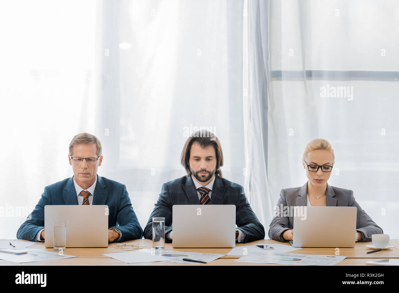 insurance workers sitting at table and using laptops in office Stock ...