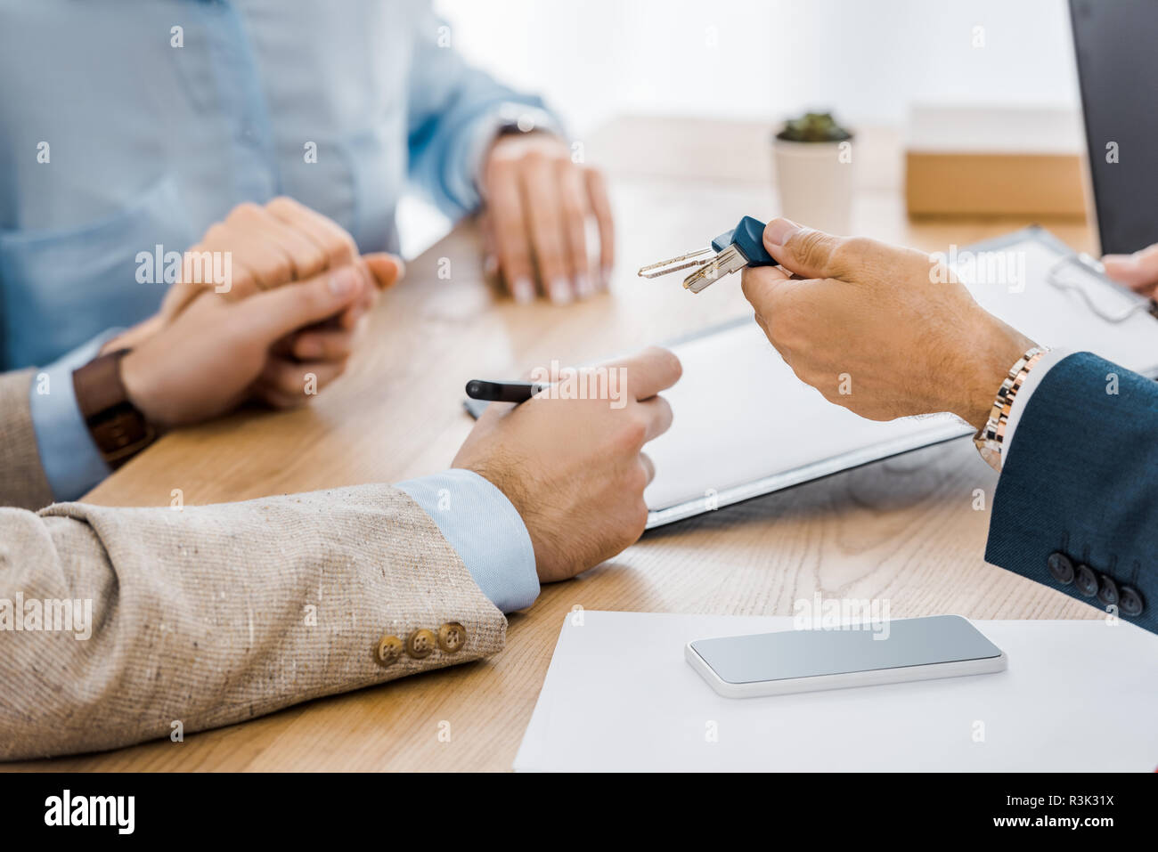 man holding keys while couple holding hands together Stock Photo - Alamy