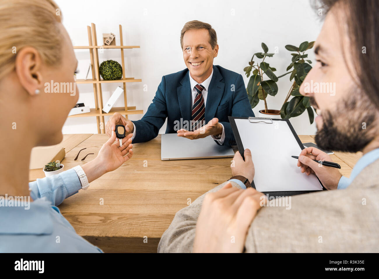 smiling businessman giving key to woman while man signing papers Stock ...