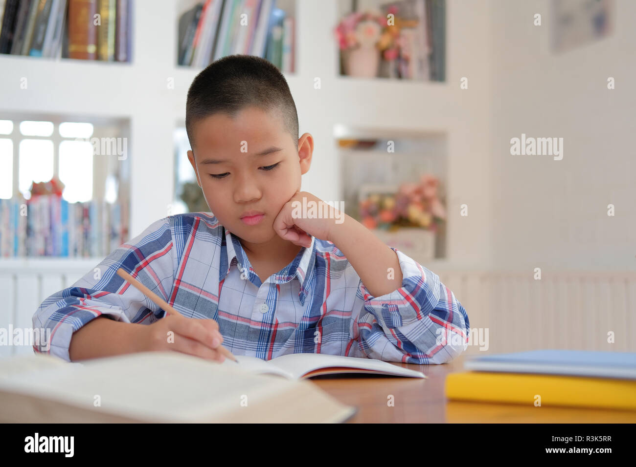 young little asian kid boy schoolboy writing drawing on notebook. child ...