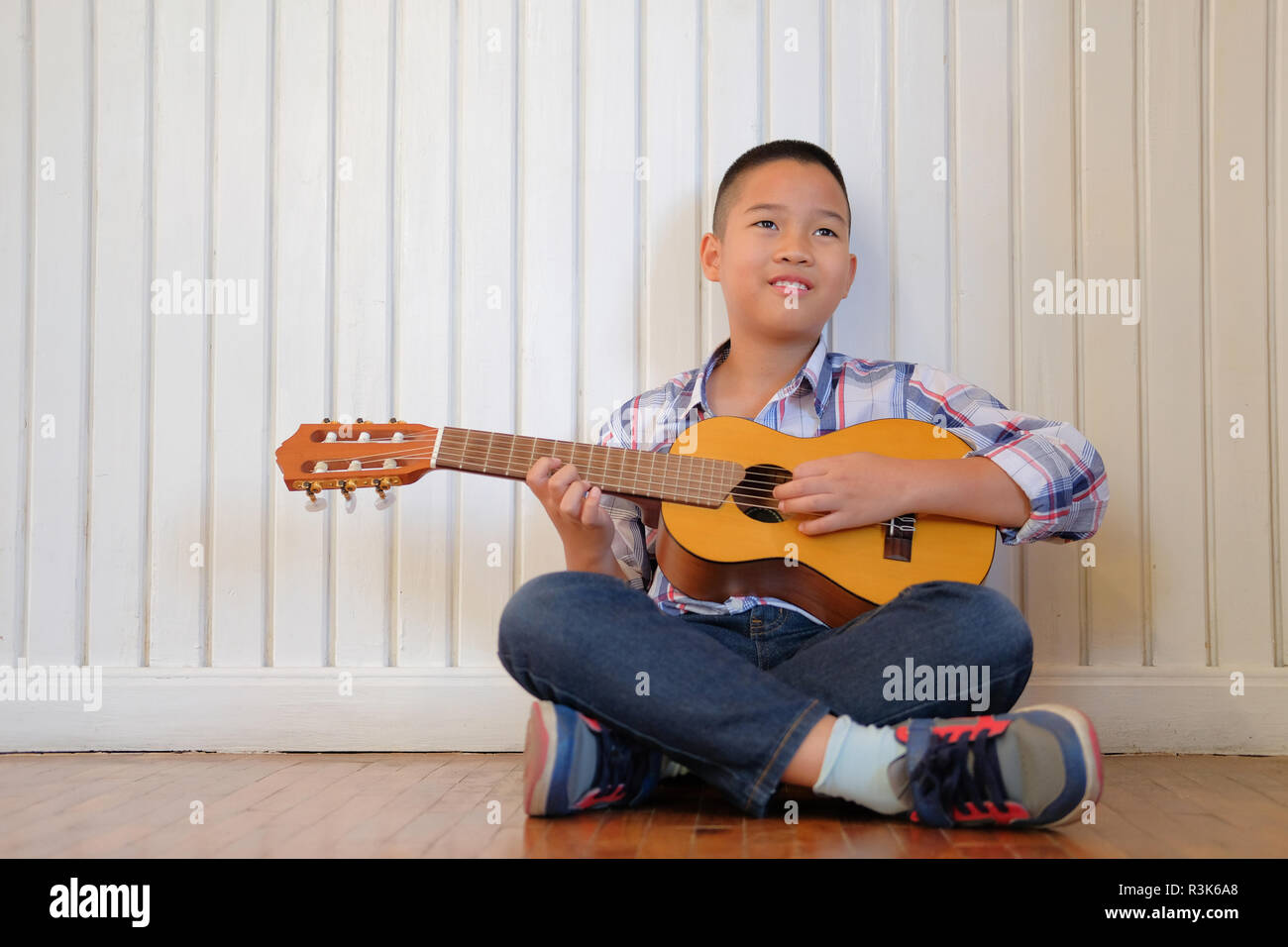 asian kid boy child playing guitar ukulele at home. children leisure ...