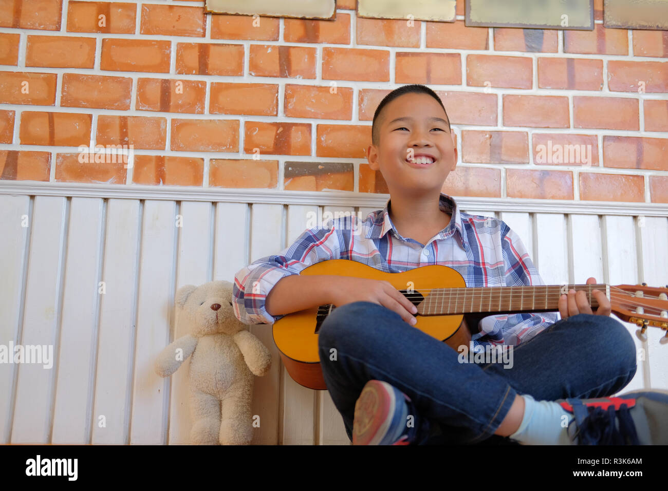 asian kid boy child playing guitar ukulele at home. children leisure ...