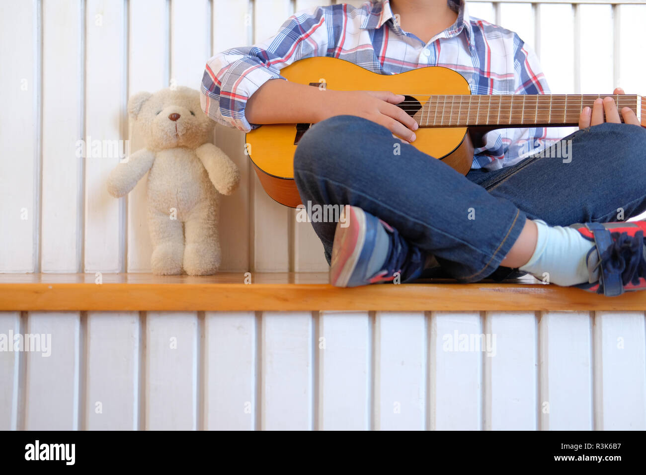 asian kid boy child playing guitar ukulele at home. children leisure ...