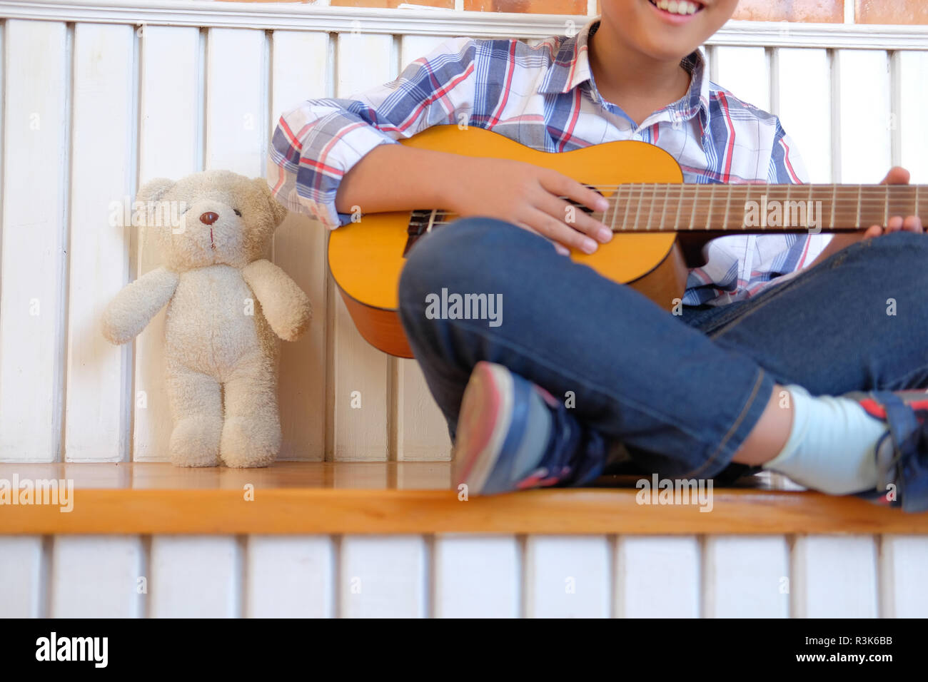 asian kid boy child playing guitar ukulele at home. children leisure ...