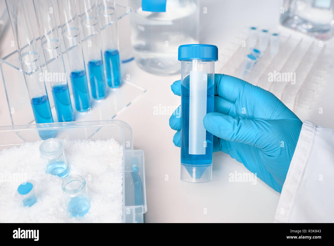 Scientific background in white and blue. Liquid sample in gloved female ...