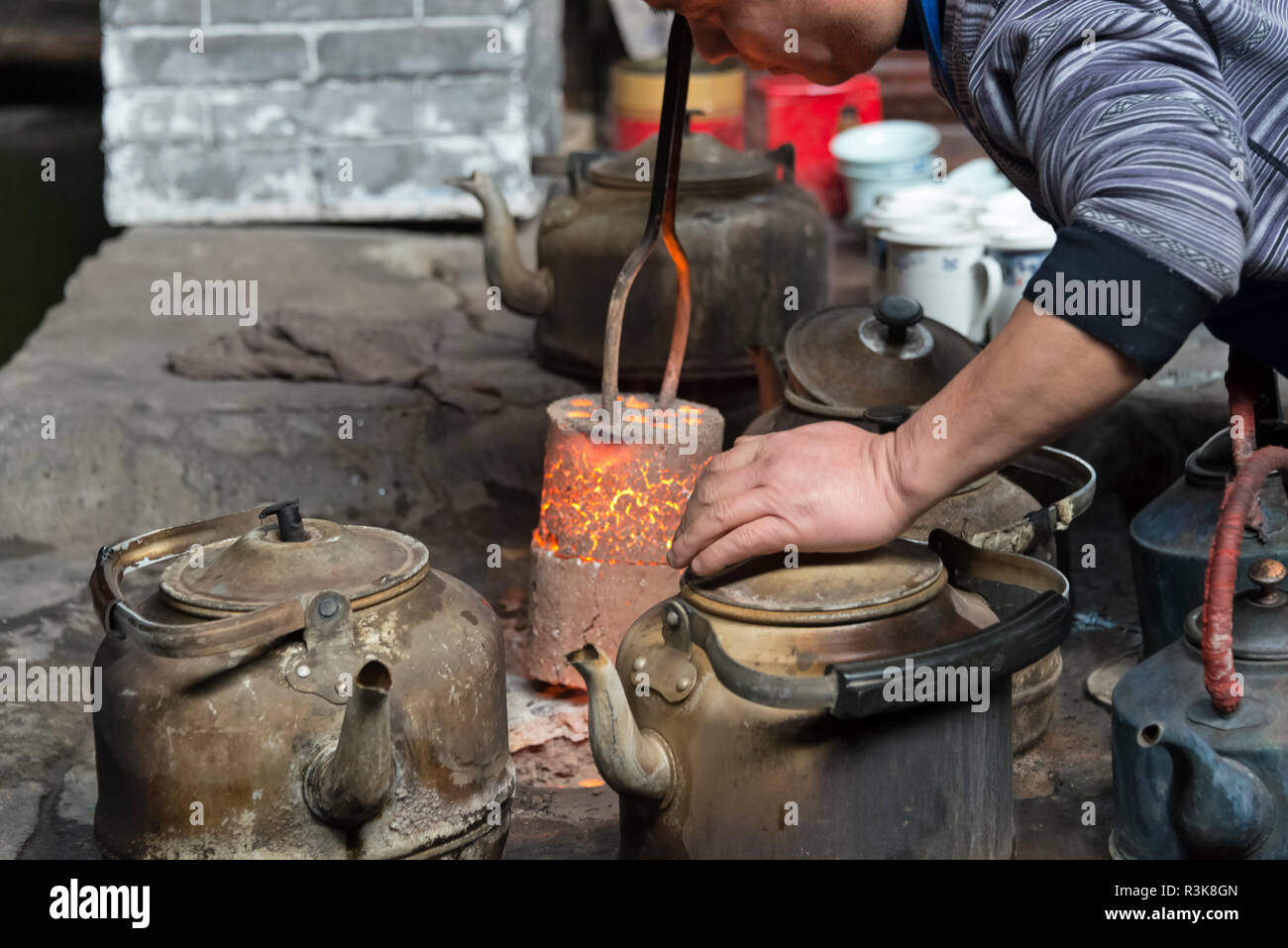 Changing coal briquette in the kitchen of an old teahouse, Pengzhen ...