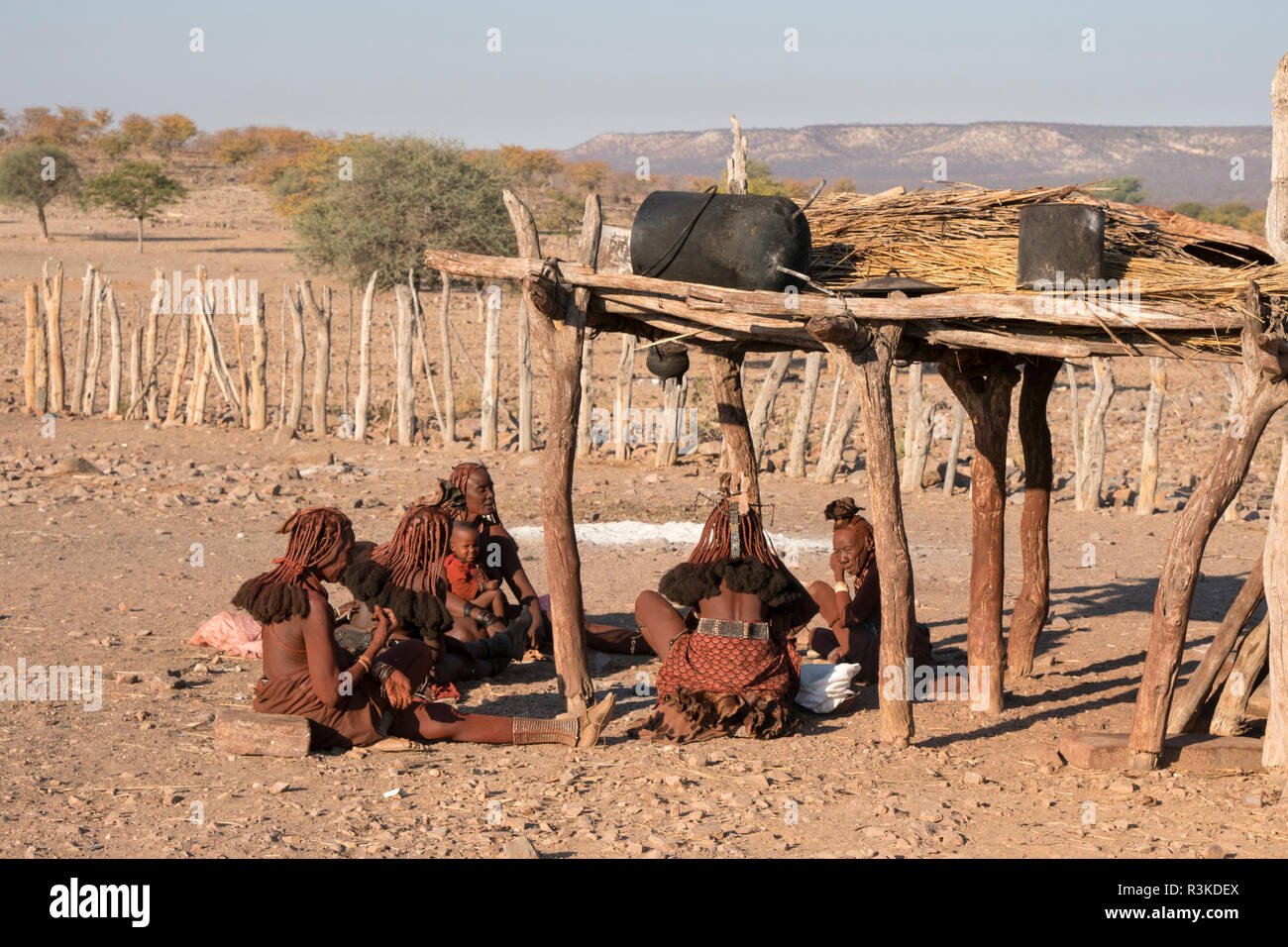 Himba women of one village gather to talk and prepare food in a remote ...