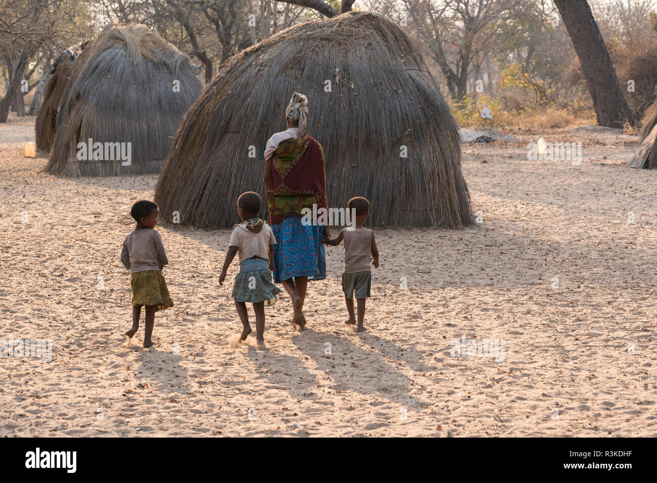Mother walking with her children in a San Bushman village in eastern ...