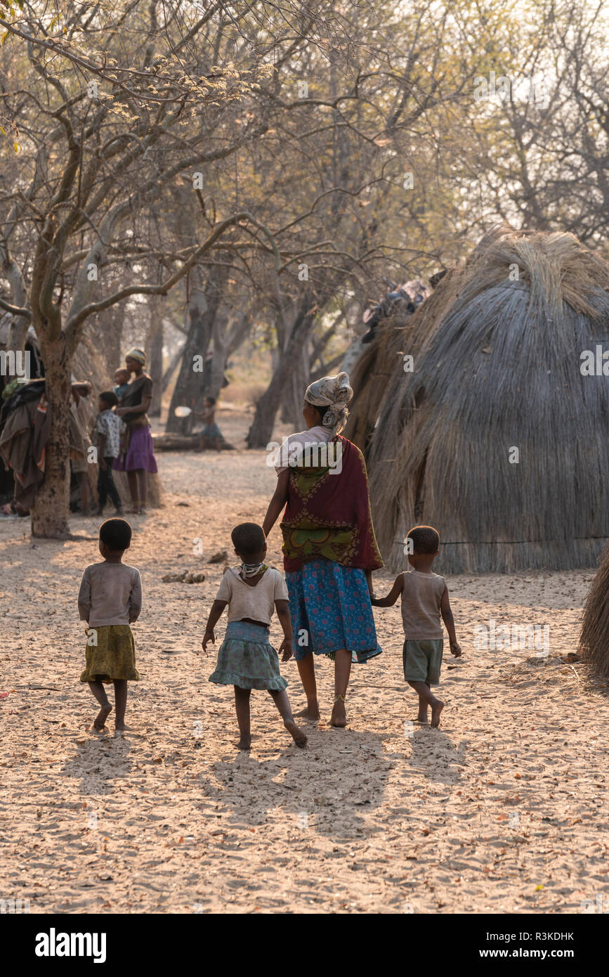 Mother walking with her children in a San Bushman village in eastern ...