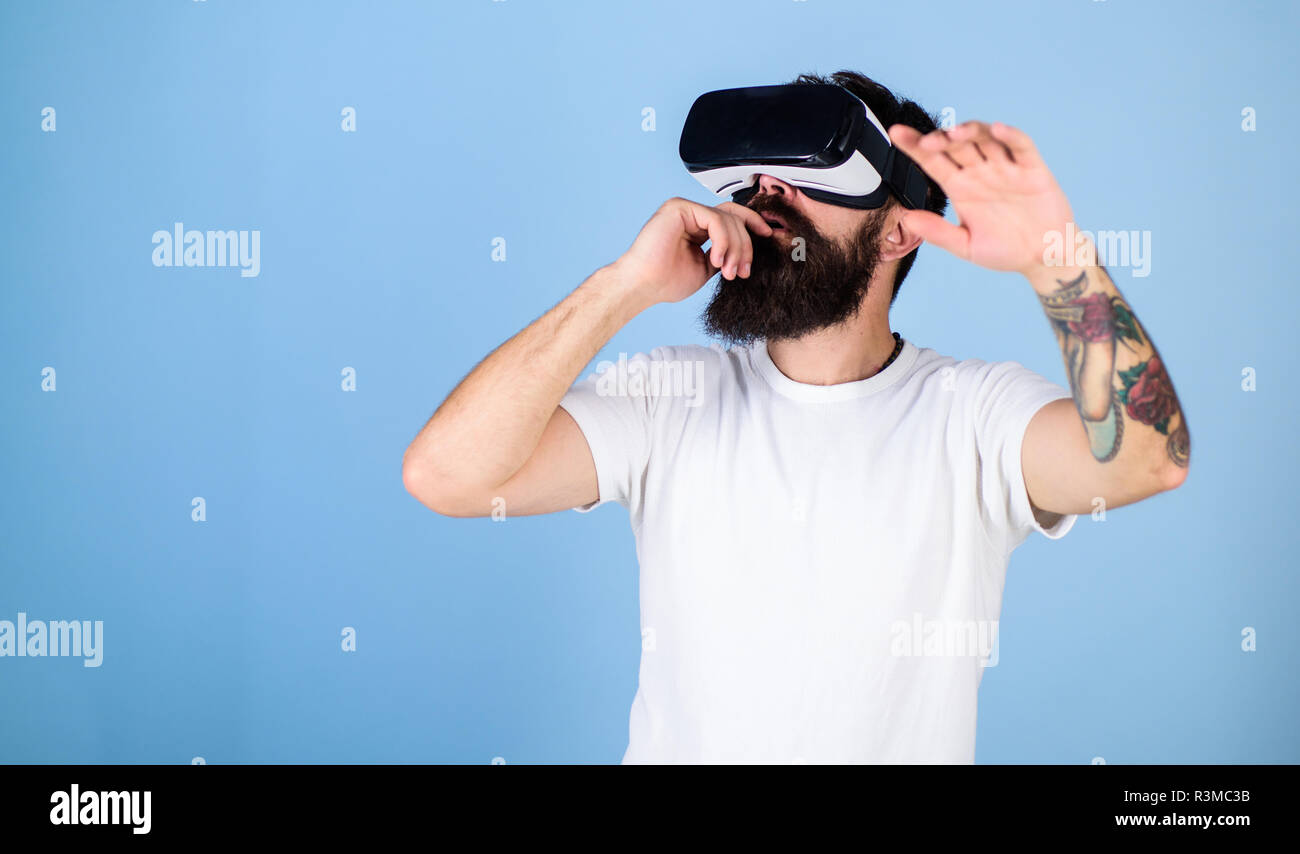 Man with beard in VR glasses, light blue background. Hipster on busy ...