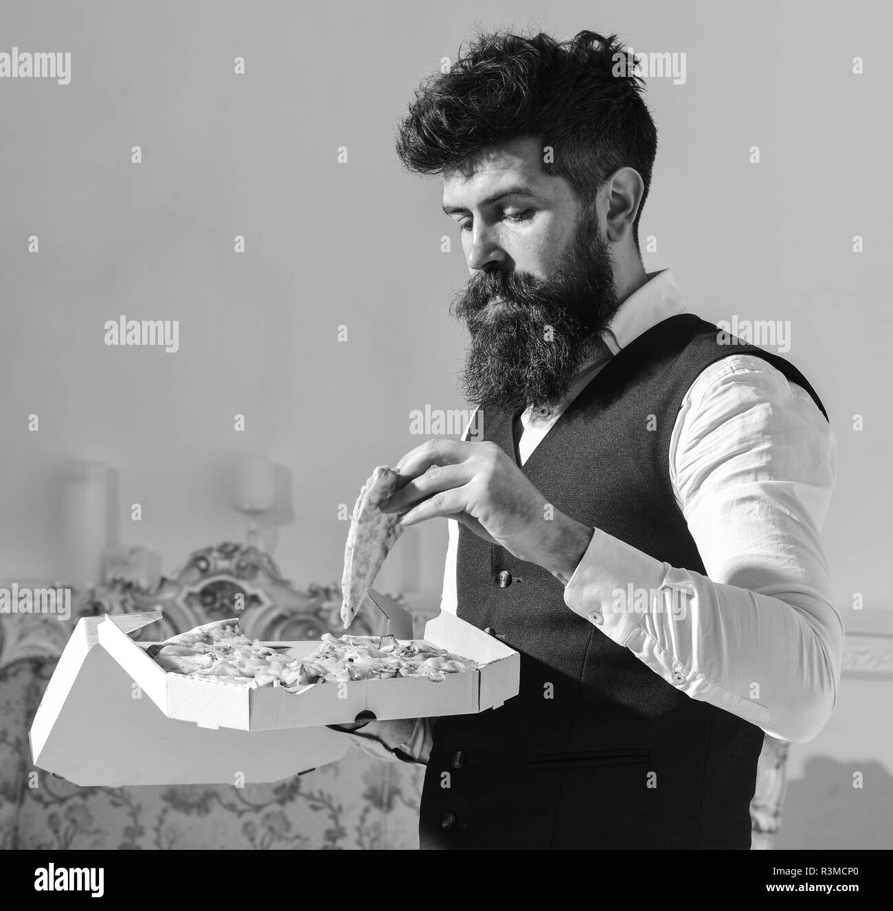 Macho in classic clothes hungry, holds slice of cheese pizza, eats ...