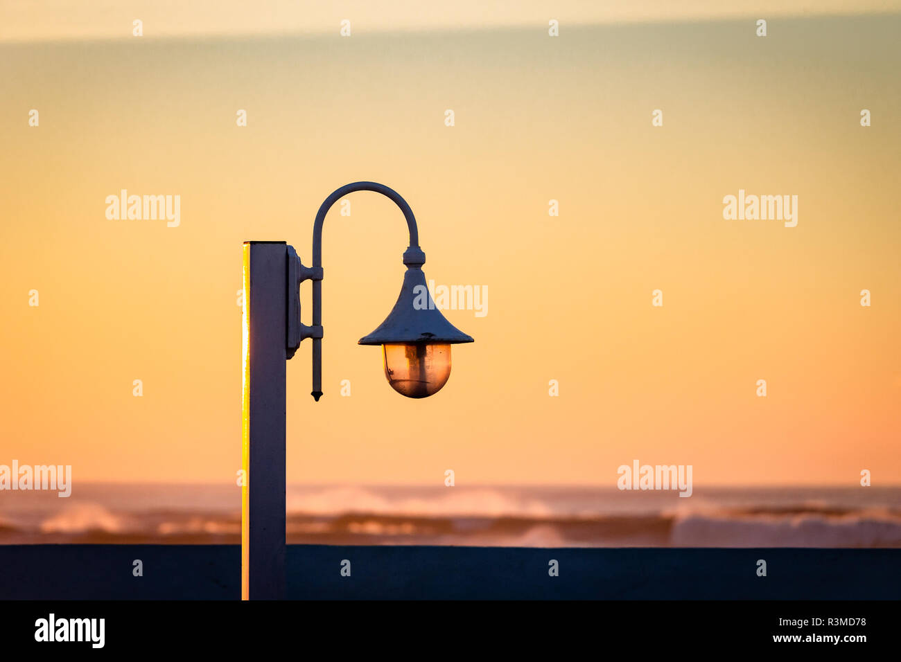 Street lamp near the ocean at sunset. Golden hour, warm light. Copy ...