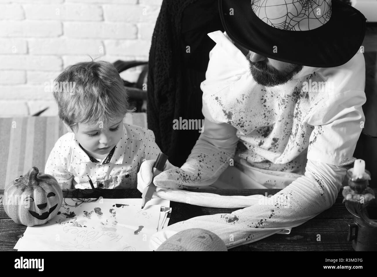 Witcher and little magician make Halloween decor. Guy and boy on rustic ...