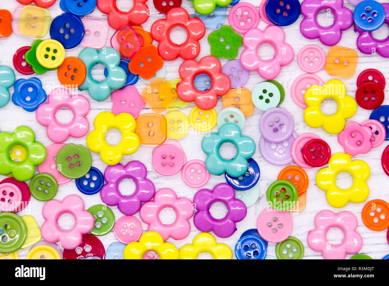A collection of colourful sewing buttons and beads on a painted white ...