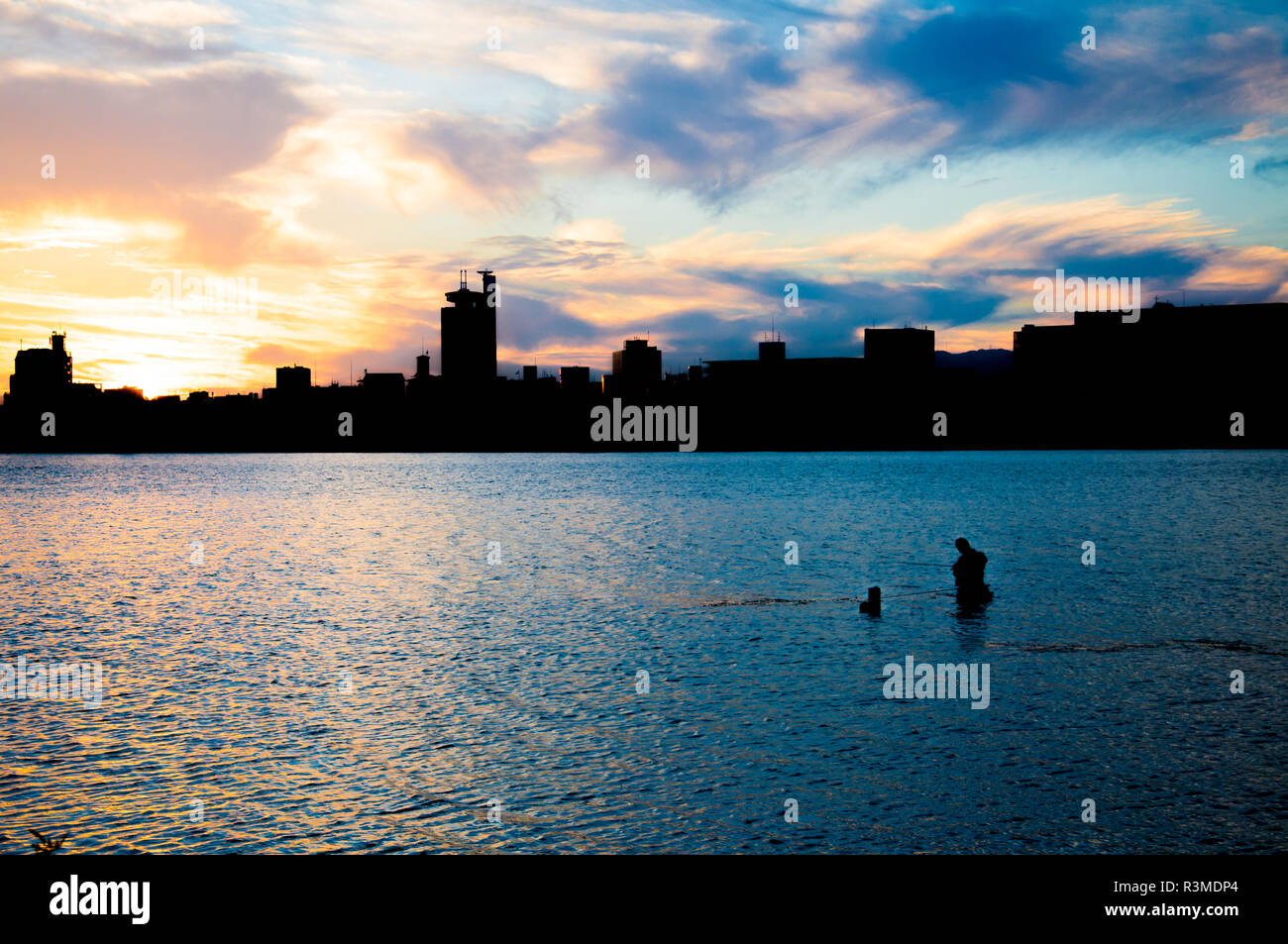 Fisher man fishing with spinning rod in a river at sunset Stock Photo ...
